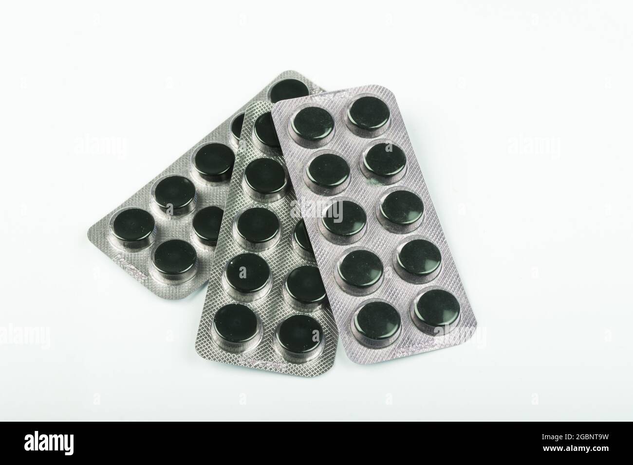 Top view closeup of three blister pack black drugs on a white ...