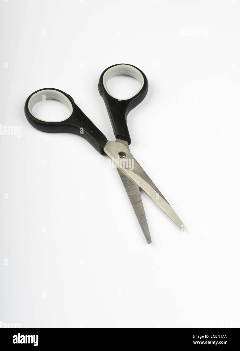Top view closeup of a pair of black scissors placed on a blank white ...