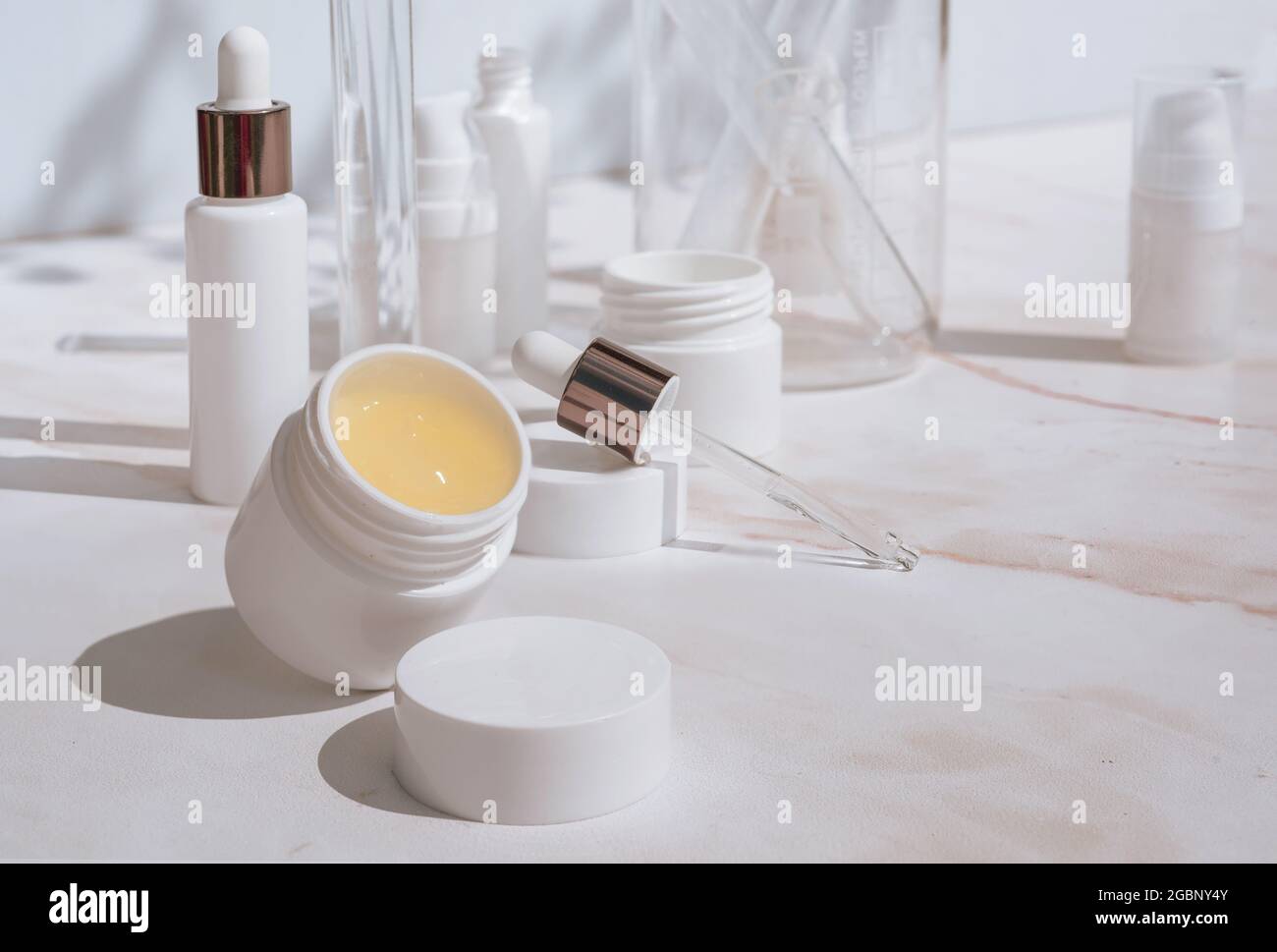 Natural cosmetic products in white packaging with laboratory glassware ...