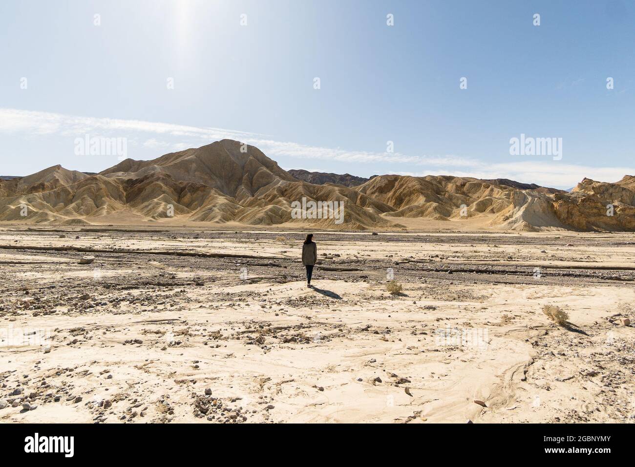 Woman walking alone in the Death Valley under a scorching sun ...