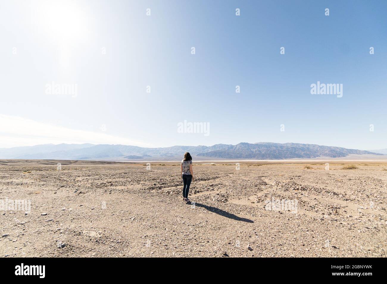 Woman wandering alone in the Death Valley under a clear sky with a ...