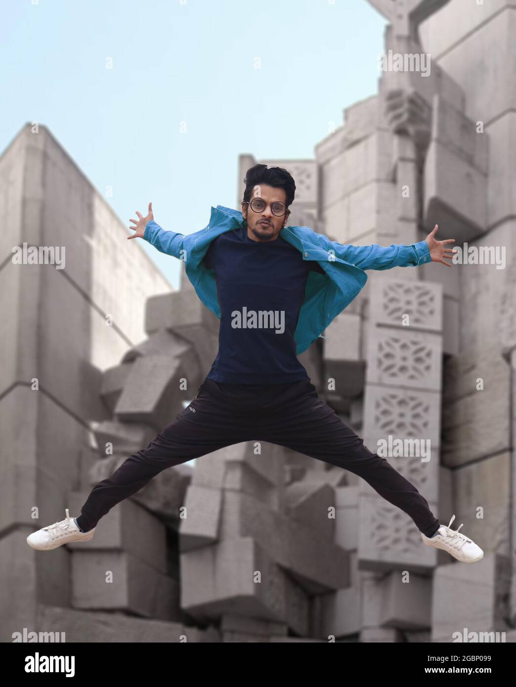 Vertical shot of a South Asian male jumping and posing in a historic ...