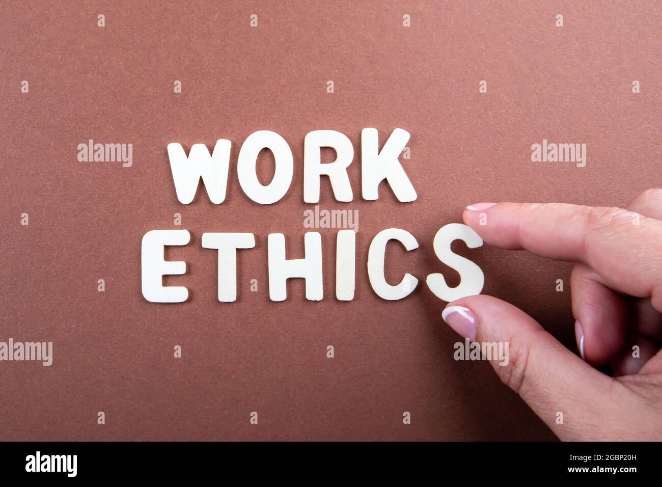 Work Ethics concept. Alphabet letters and a woman's hand on brown ...