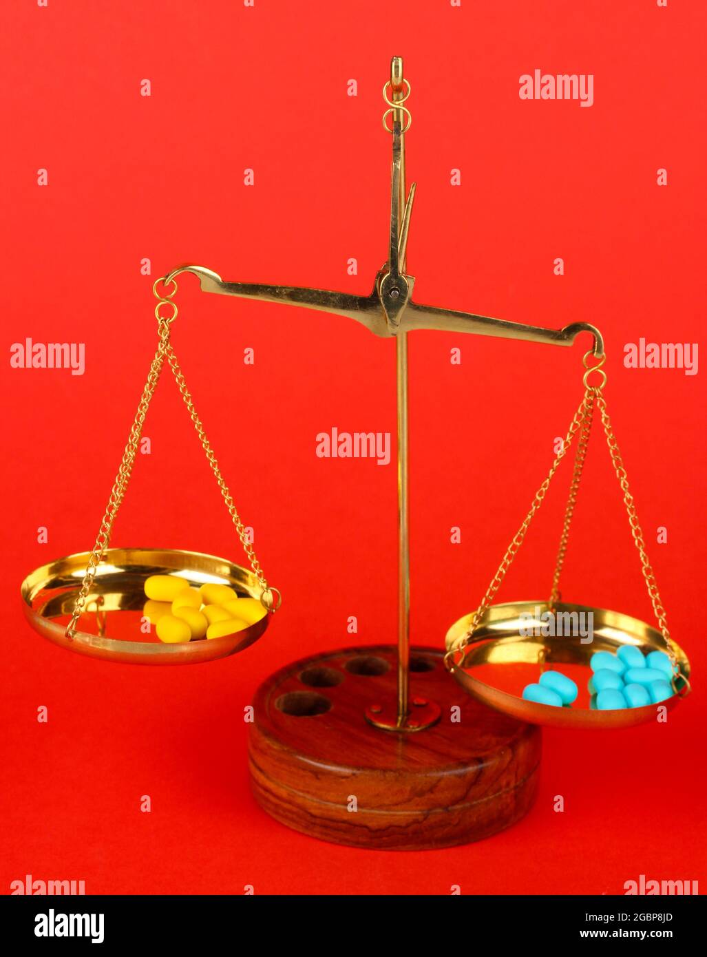 Classic scales with color pills on color background Stock Photo - Alamy