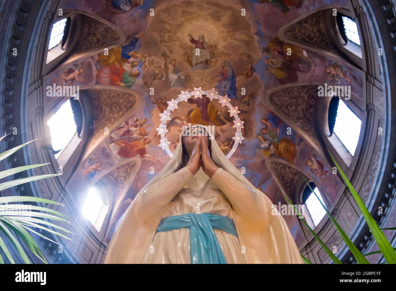 A sculpture, statue of the Virgin Mary, with white robe, blue sash and ...