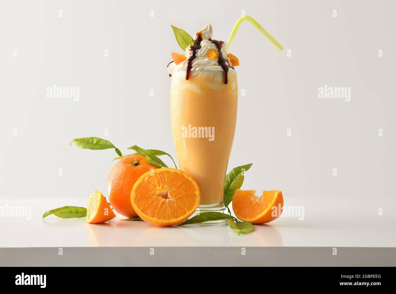 Orange milkshake with cream decorated with fruit and leaves around on ...