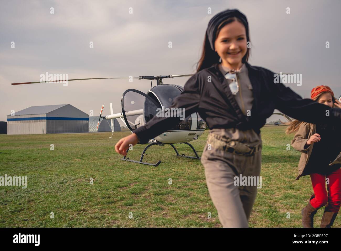 Cheerful tween girl running on background of helicopter on airfield ...
