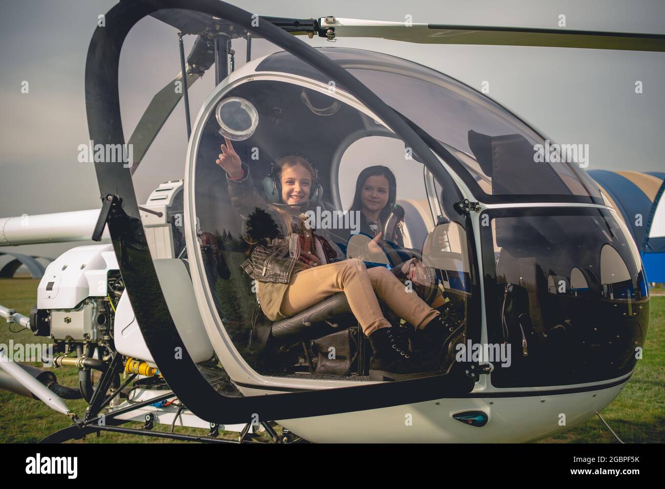Cheerful tween girl pointing to sky from helicopter cockpit Stock Photo ...