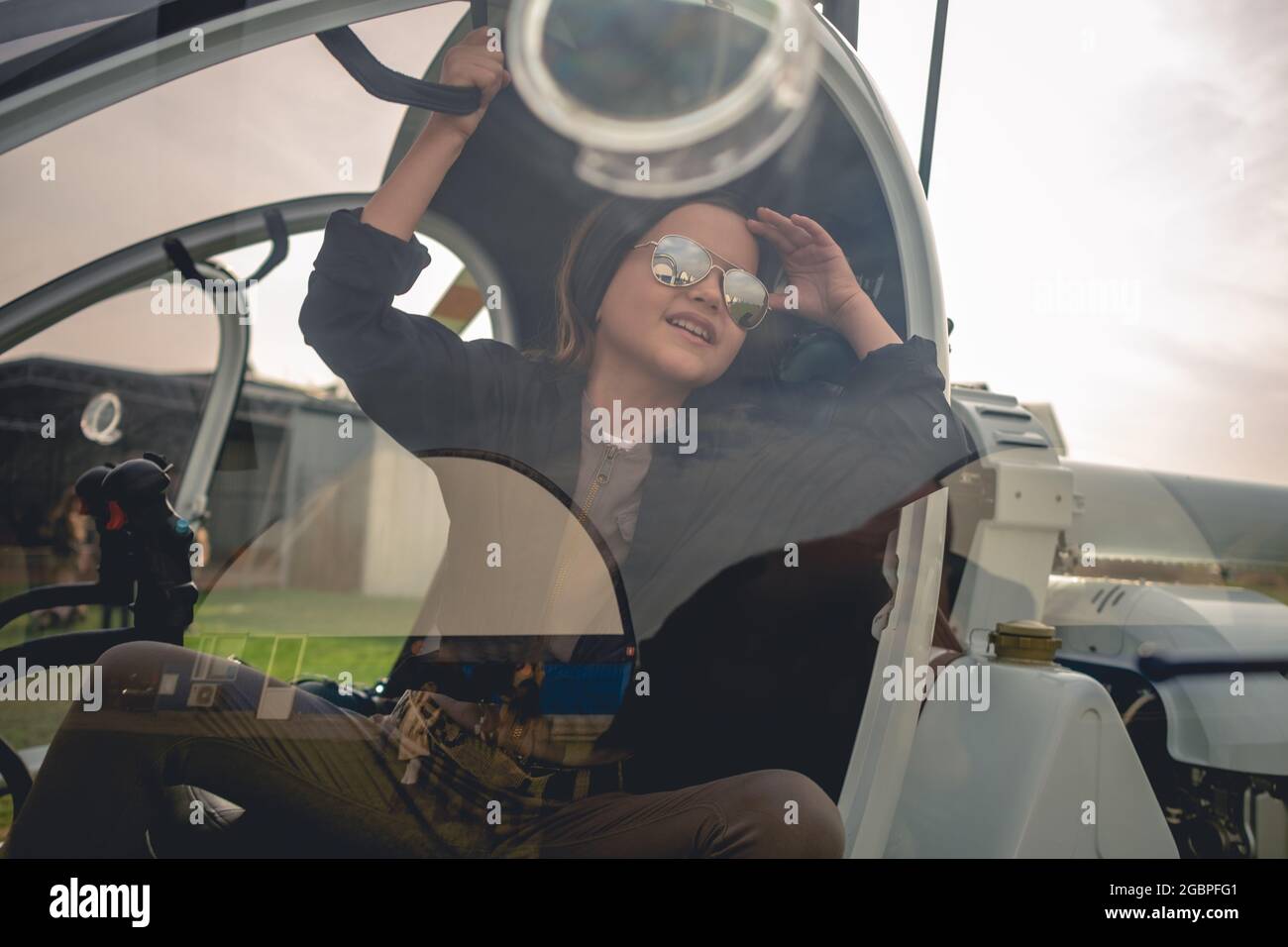 View through glass of helicopter cockpit of cheerful tween girl looking ...
