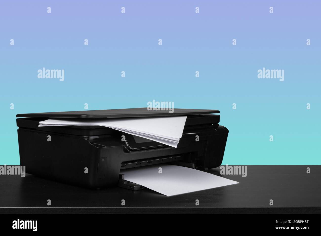 Compact laser printer on black desk against blue background Stock Photo ...