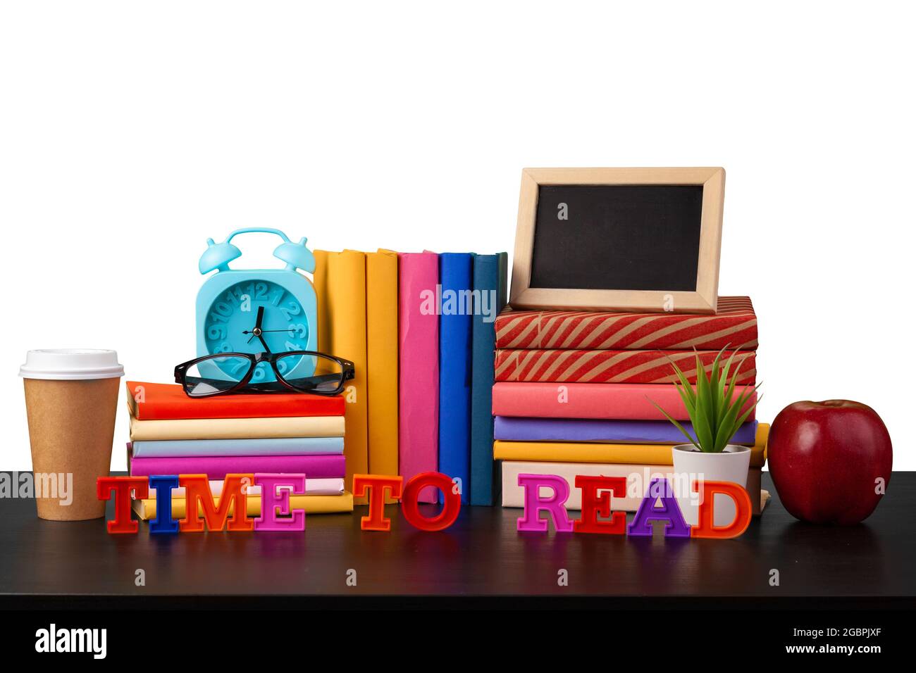 Alarm clock, stack of books and cup on tabletop against white ...