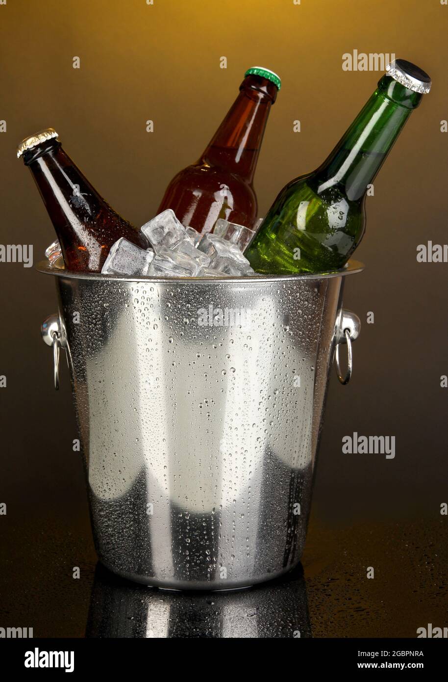 Beer bottles in ice bucket on darck yellow background Stock Photo - Alamy