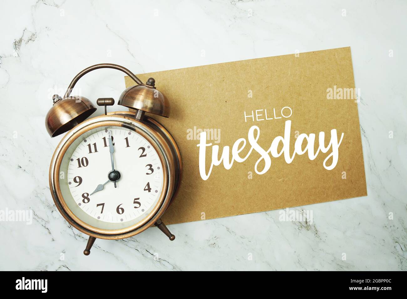 Hello Tuesday typography text on paper card with alarm clock on marble ...