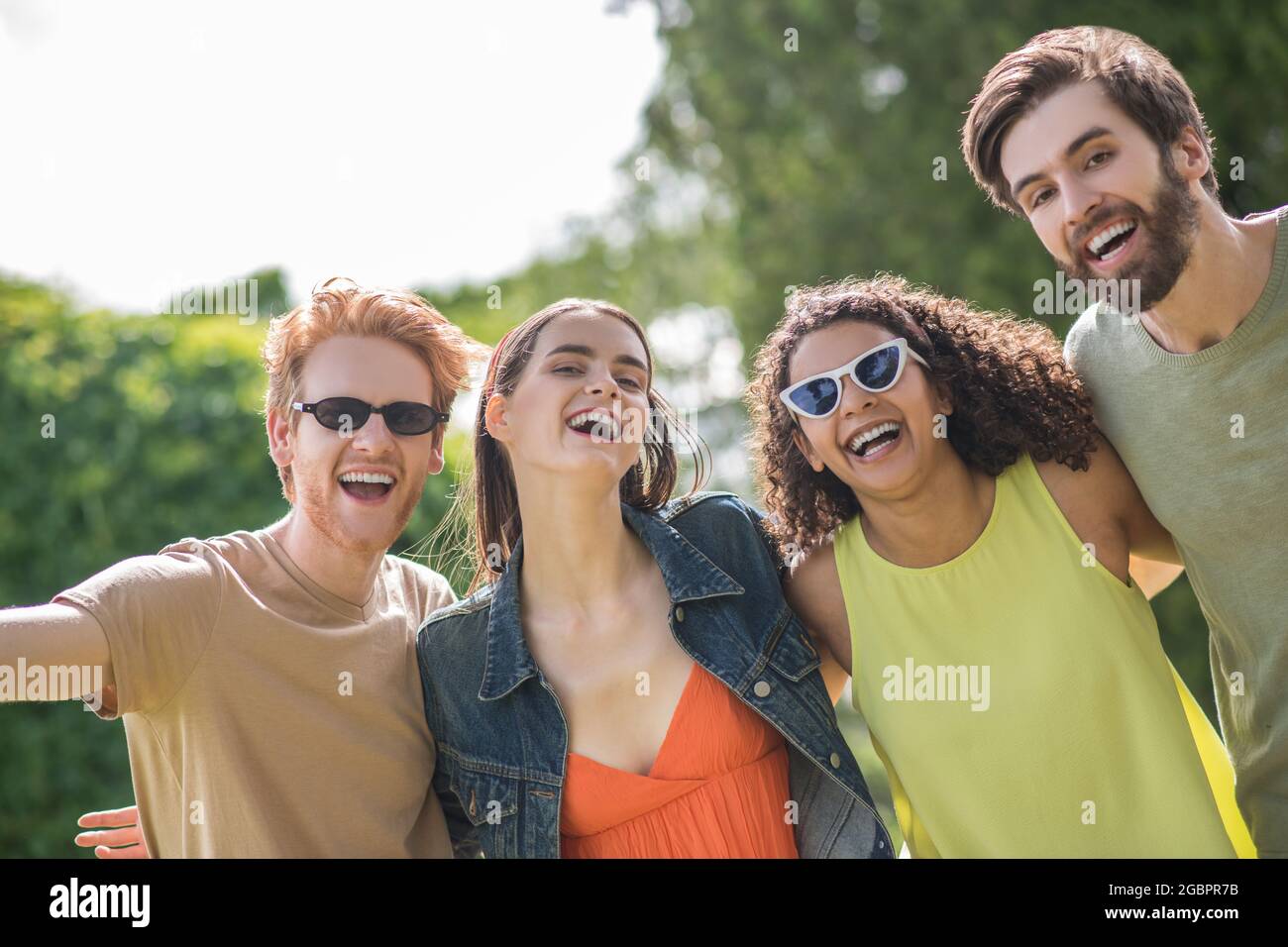 Four young joyfully smiling friends in nature Stock Photo - Alamy