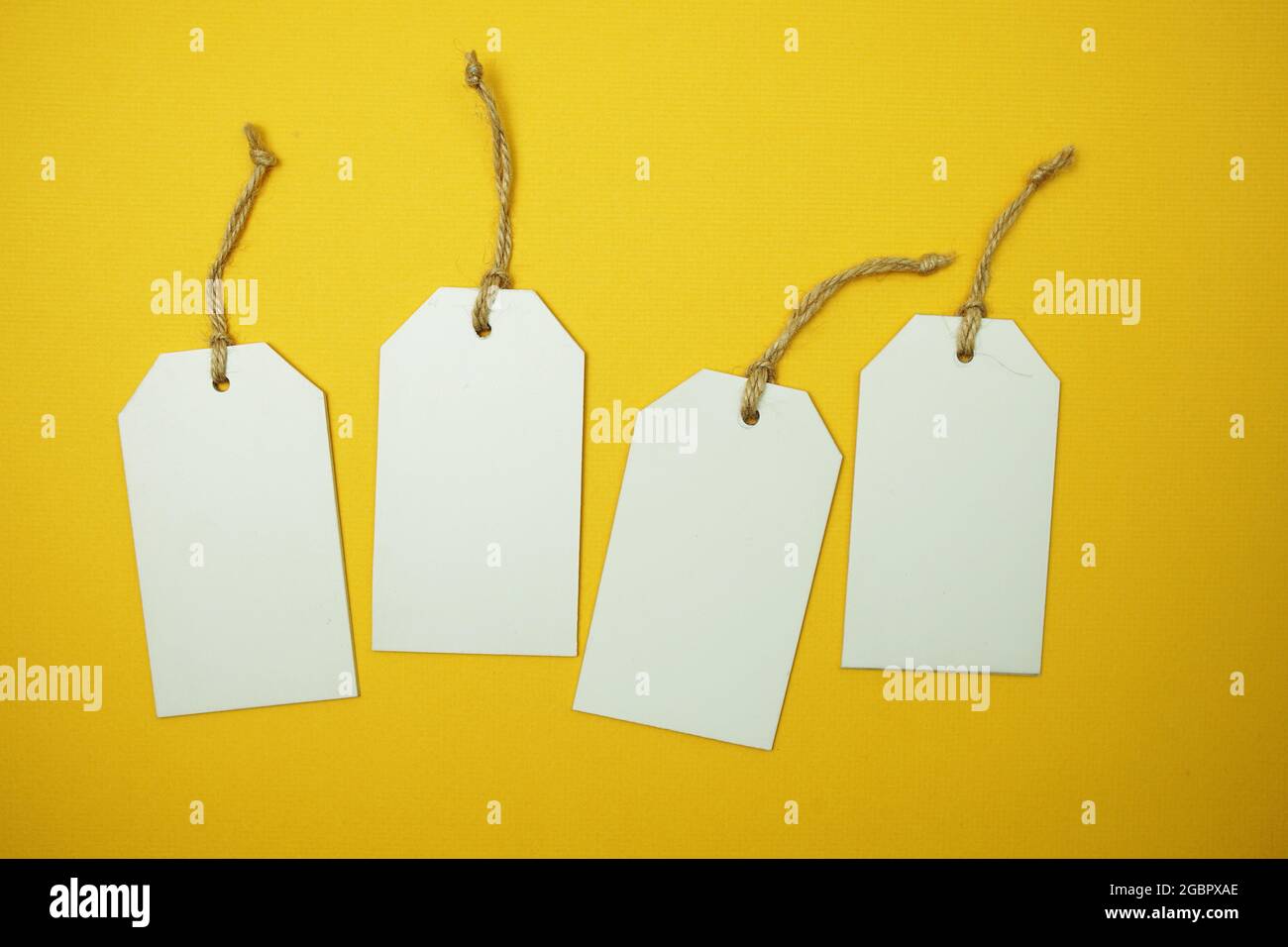 Flat lay White Blank Tag on yellow background Stock Photo - Alamy