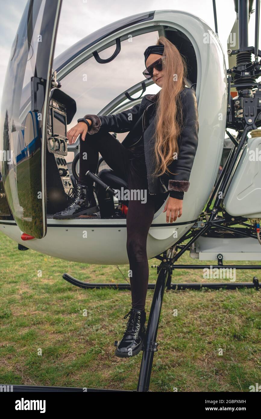 Confident tween girl in black standing on footboard of helicopter Stock ...
