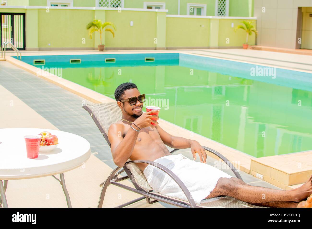 cool looking black dude chilling by the pool side with a drink in hand ...