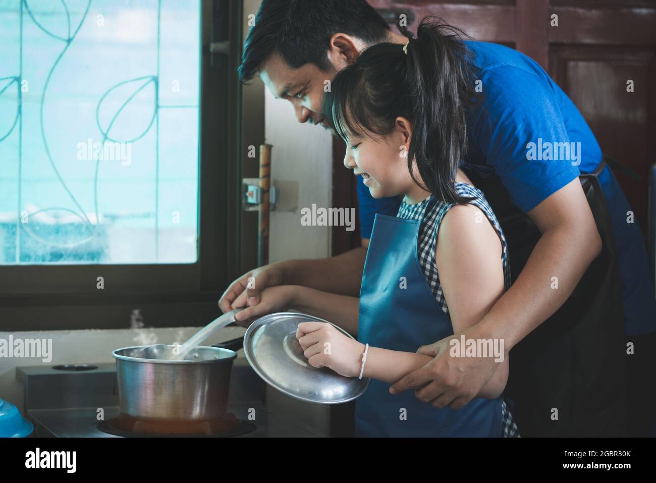Daughter and father cook together happily in the kitchen. Family ...