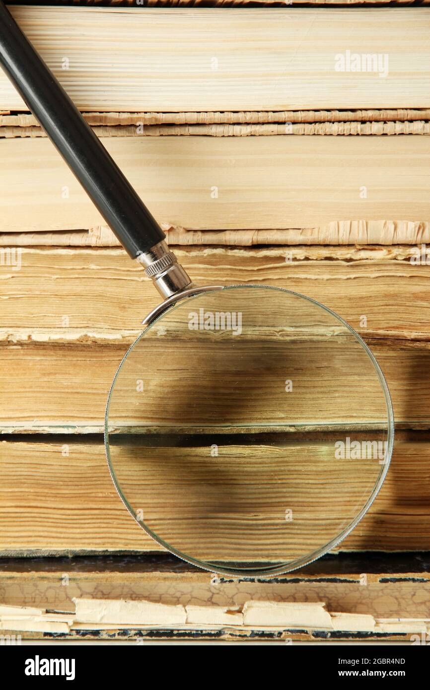 Magnifying glass over the stack of books Stock Photo - Alamy