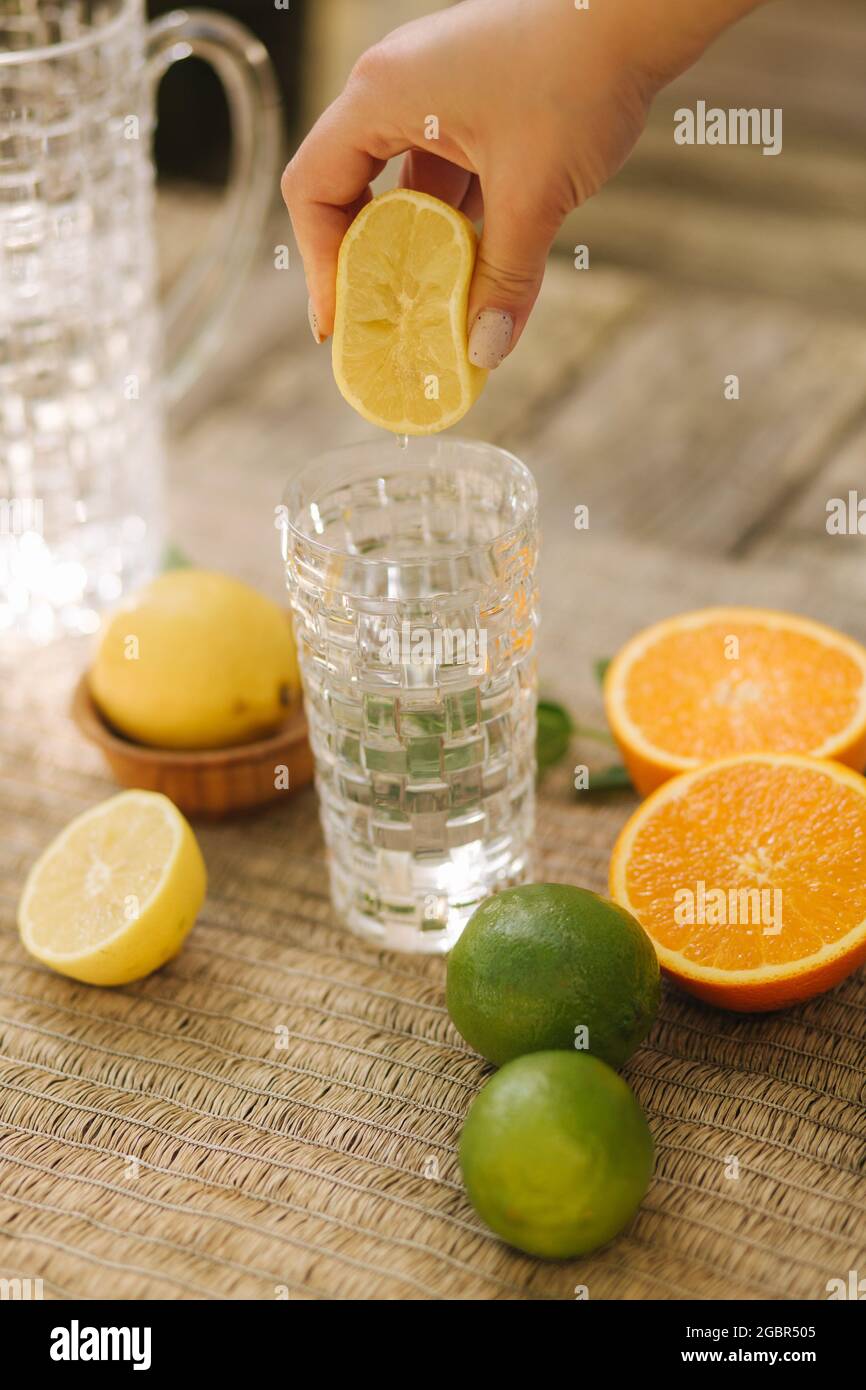 Home made healthy vitamin-fortified water. Woman squeezes lemon juice ...