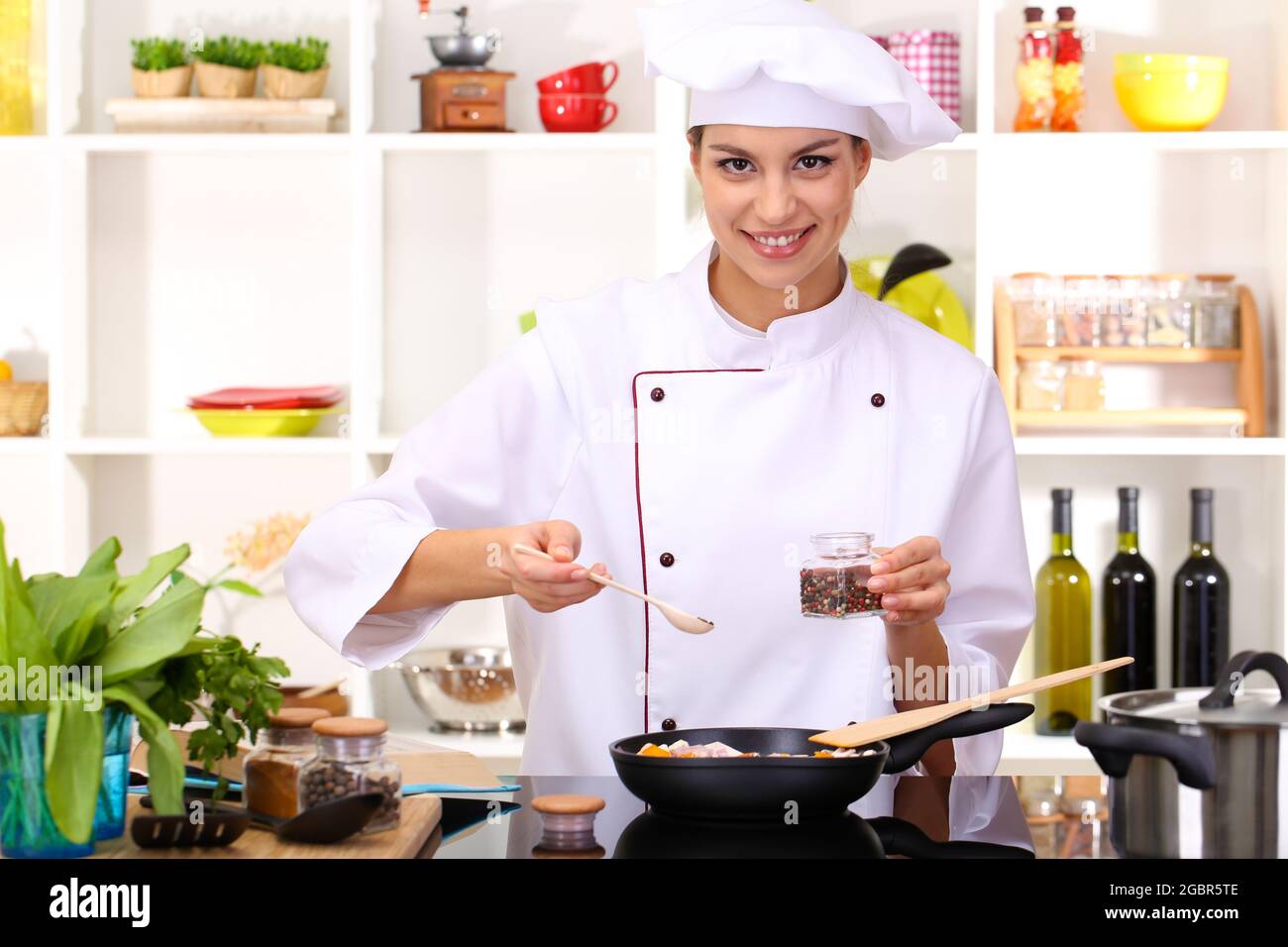 Young woman chef cooking in kitchen Stock Photo - Alamy