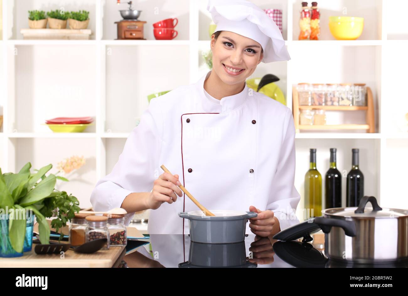 Young woman chef cooking in kitchen Stock Photo - Alamy