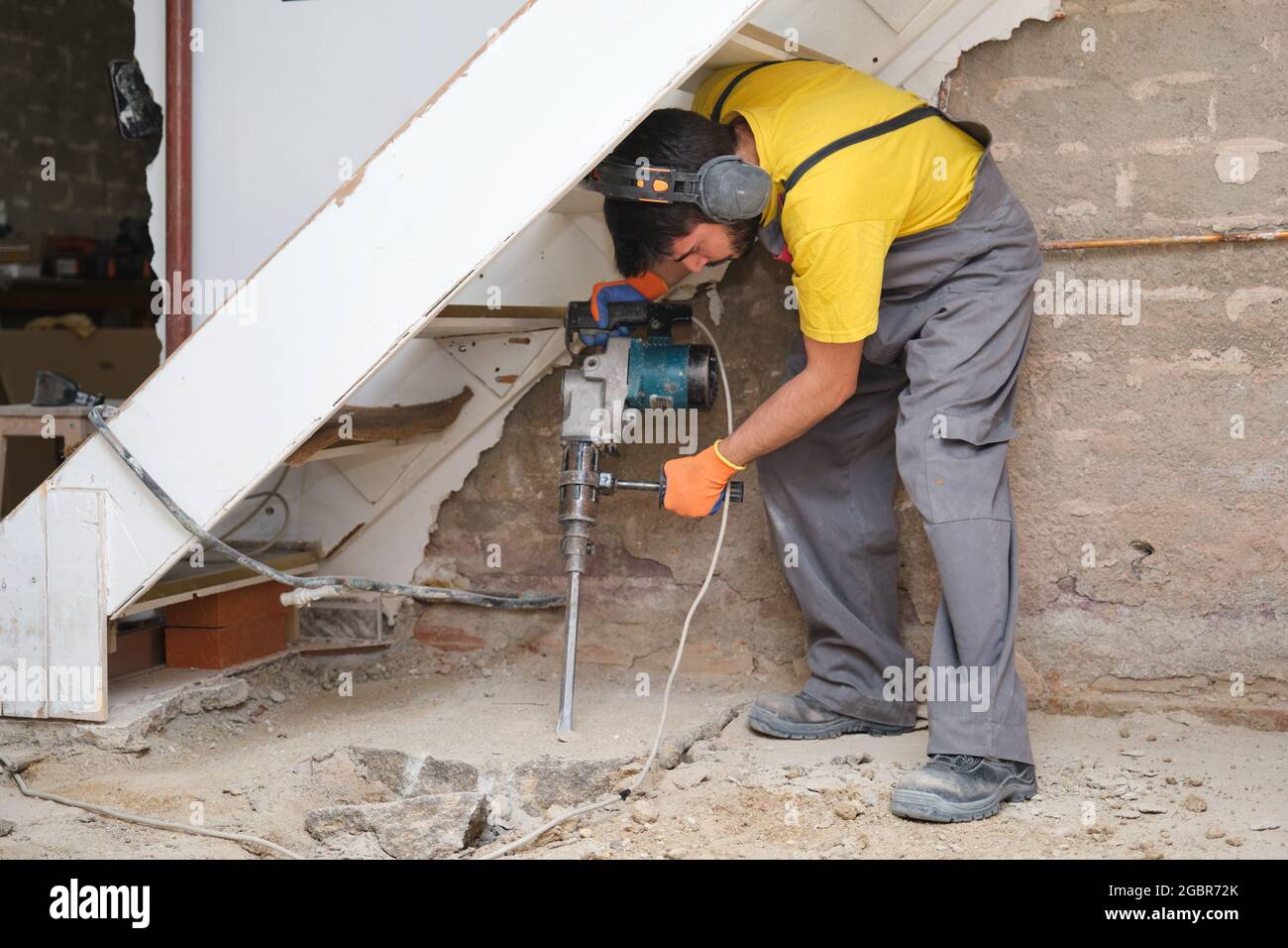 Young builder breaking up a house floor with a jackhammer Stock Photo ...