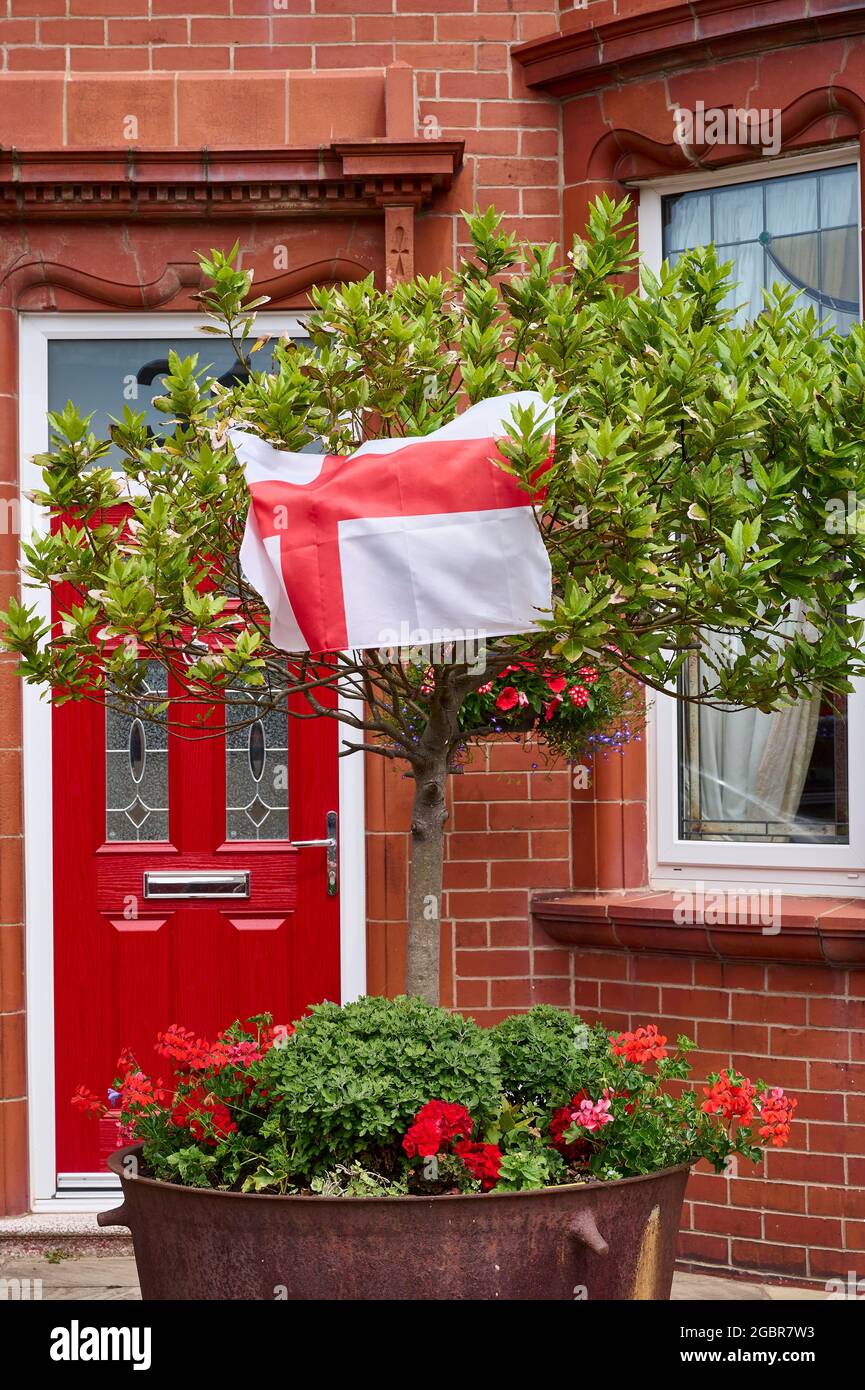 Red and white flag of St George on tree in front of red and white door Stock Photo Alamy