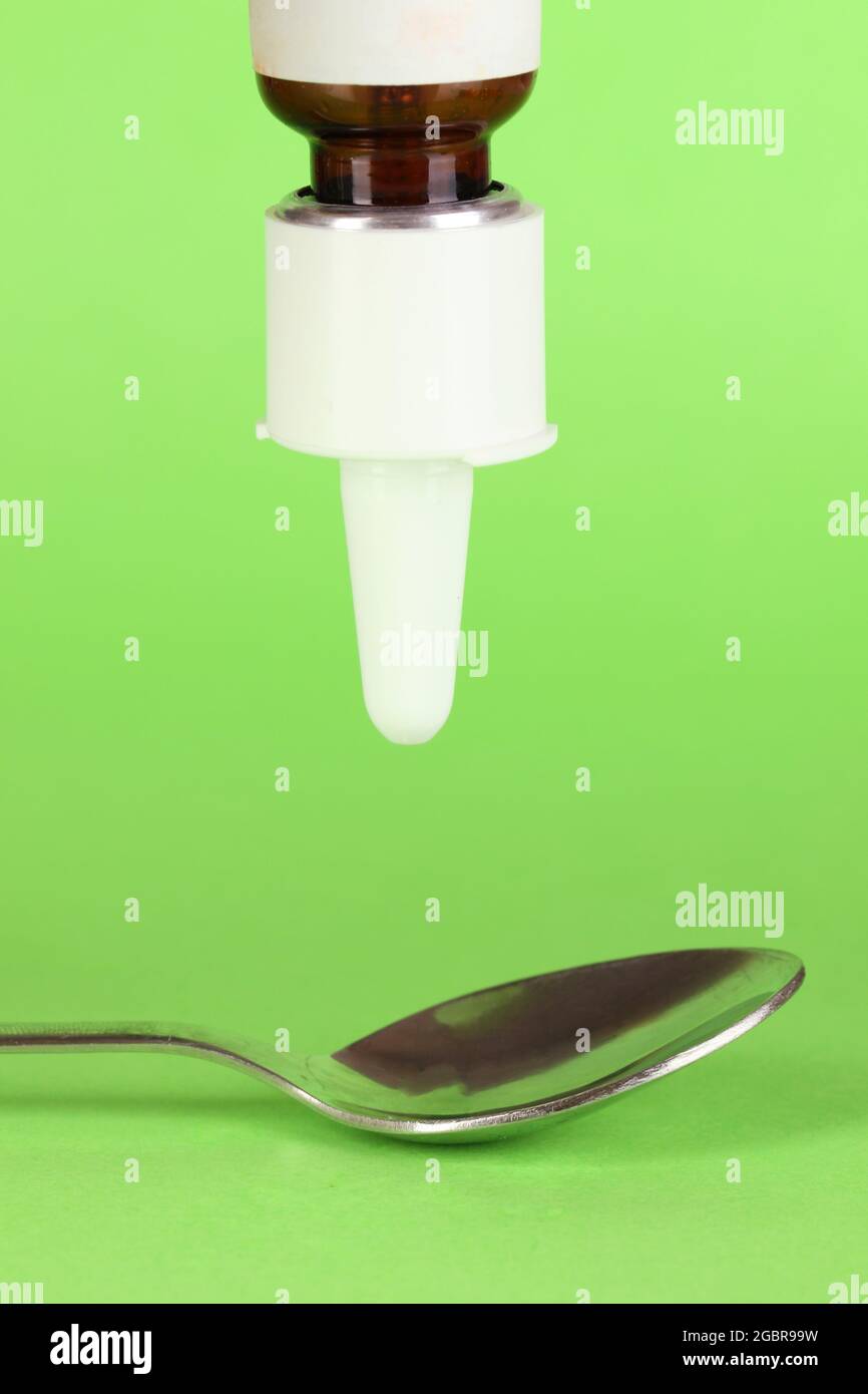 Medical droplet in spoon on green background Stock Photo - Alamy