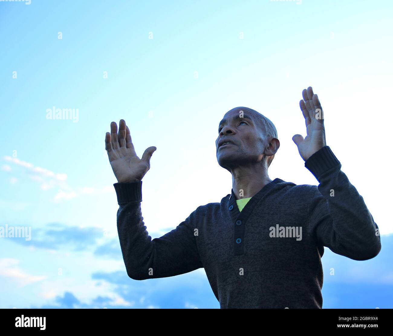 man praying to god with hands together Caribbean man praying with ...