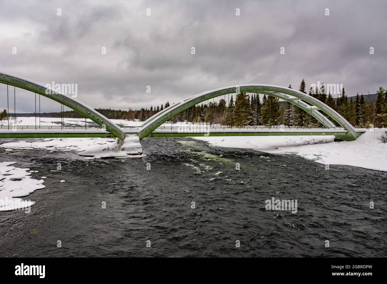 Bridge over the water covered in ice and snow on a cold gloomy winter ...
