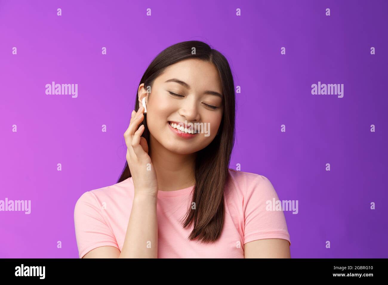 Cute asian girl enjoying listening music, put on wireless headphone ...