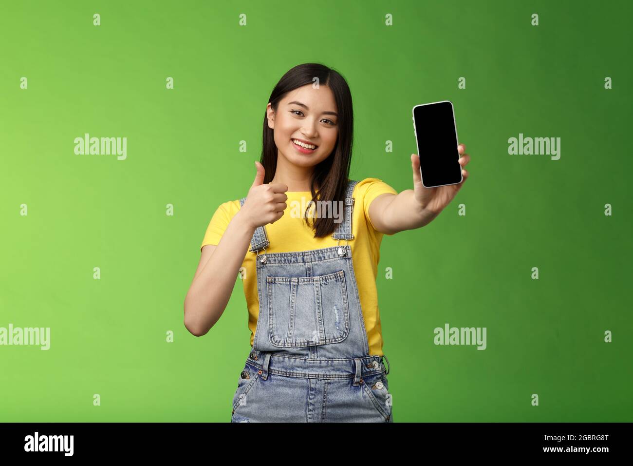 Cheerful cute asian woman judging good smartphone game, show thumb-up ...