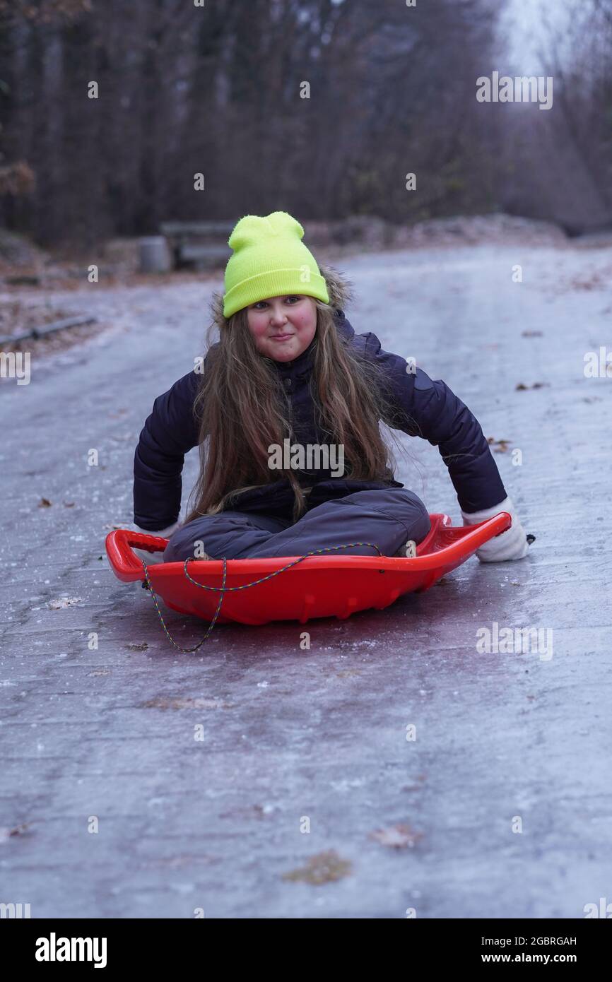 Childhood, sledging and season concept - kid funny sliding on an ice ...