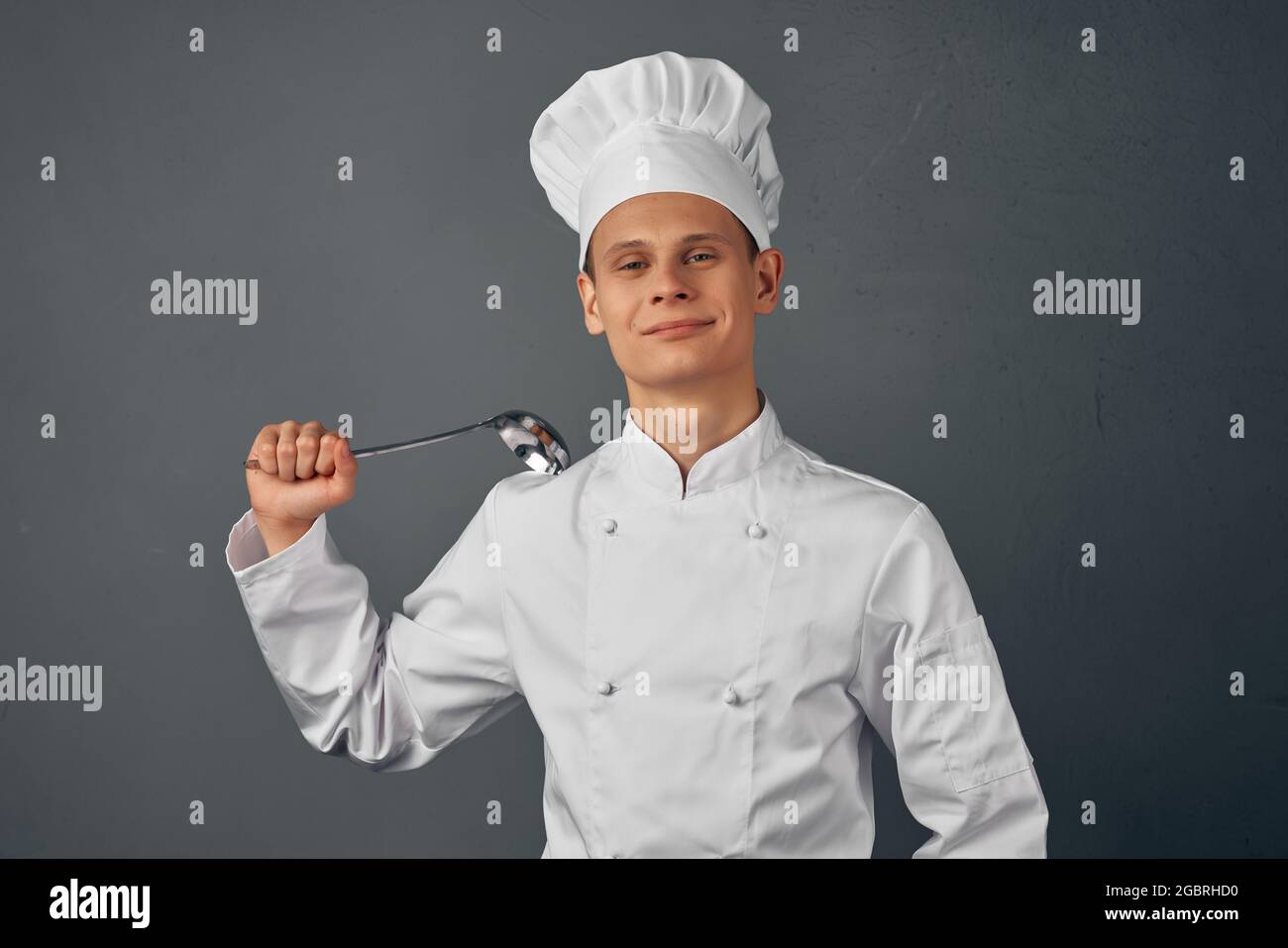 a chef with a cap on his head a scoop in his hands cooking food dark ...