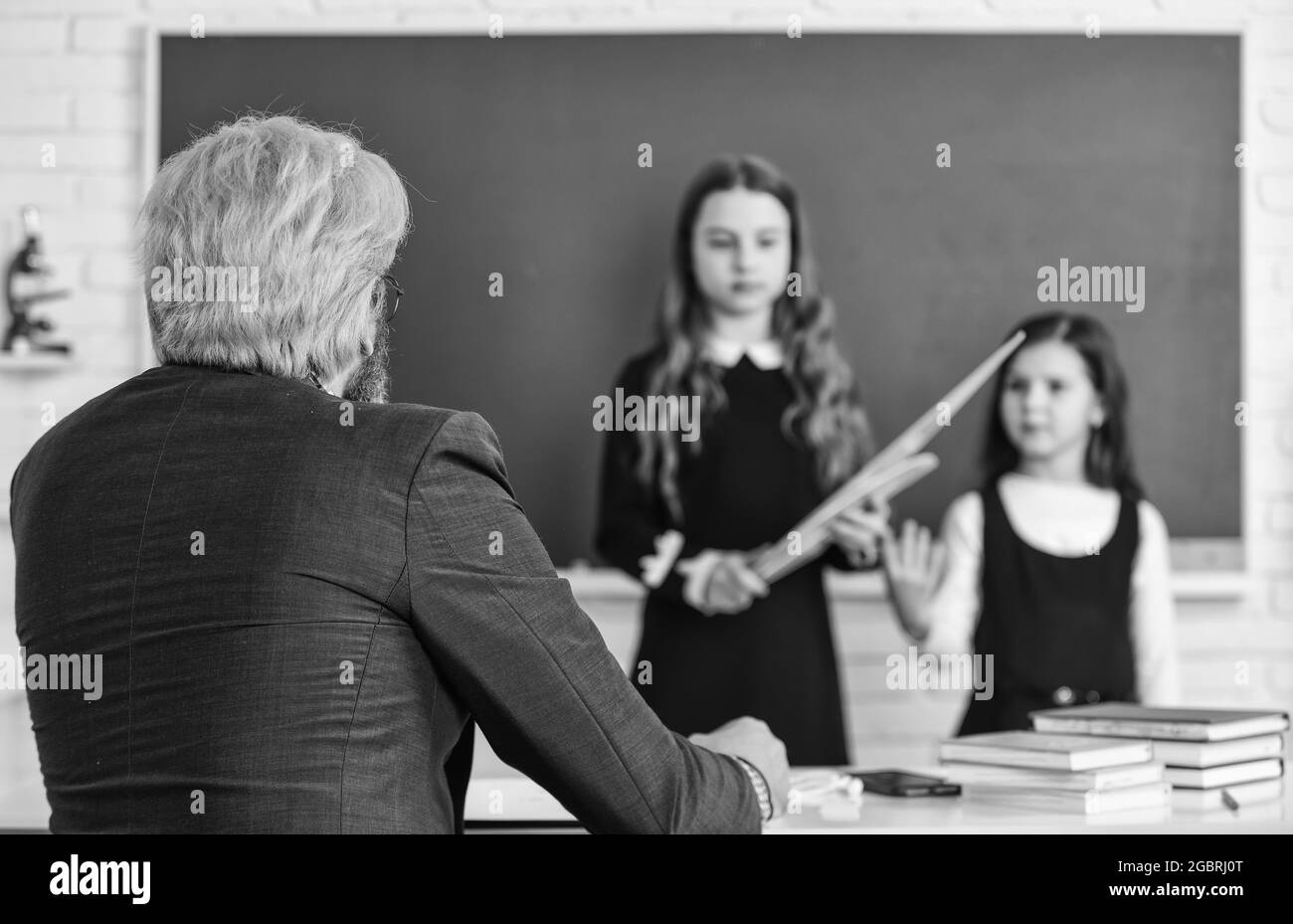 Confident students studying. Teacher and pupils working at desk ...