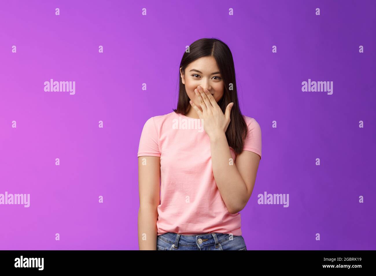 Timid cute stylish modern asian woman giggling, gossiping, cover smiling lips, laughing out loud ...