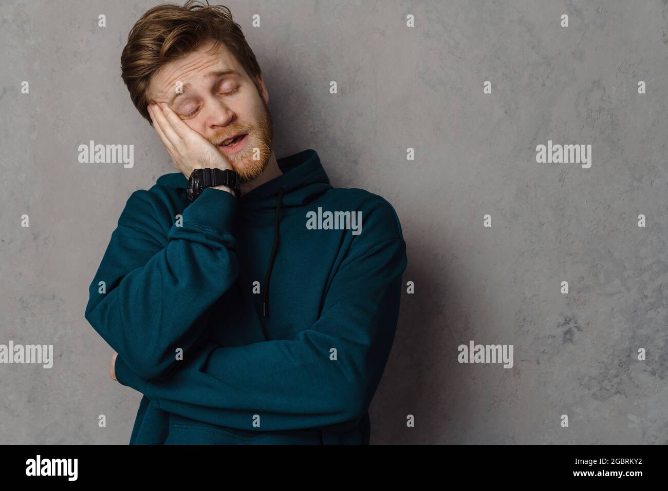 Bearded ginger man looking at camera while propping up his head ...