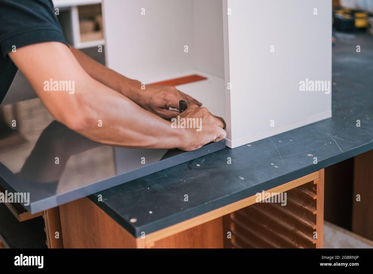 Hands of a man fixing a hinge on a surface for a kitchen Stock Photo ...