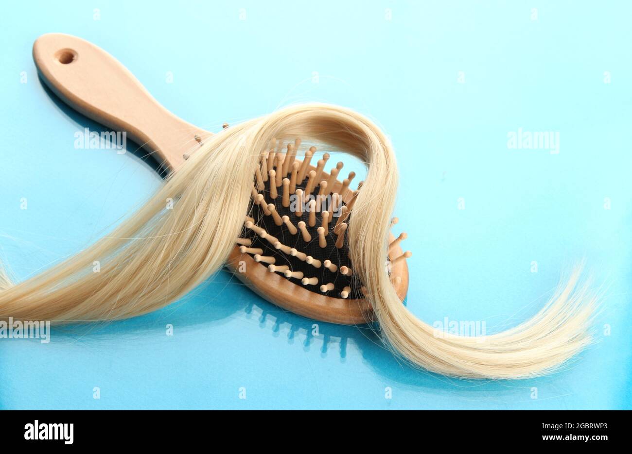 wooden comb brush with hair, on blue background Stock Photo - Alamy