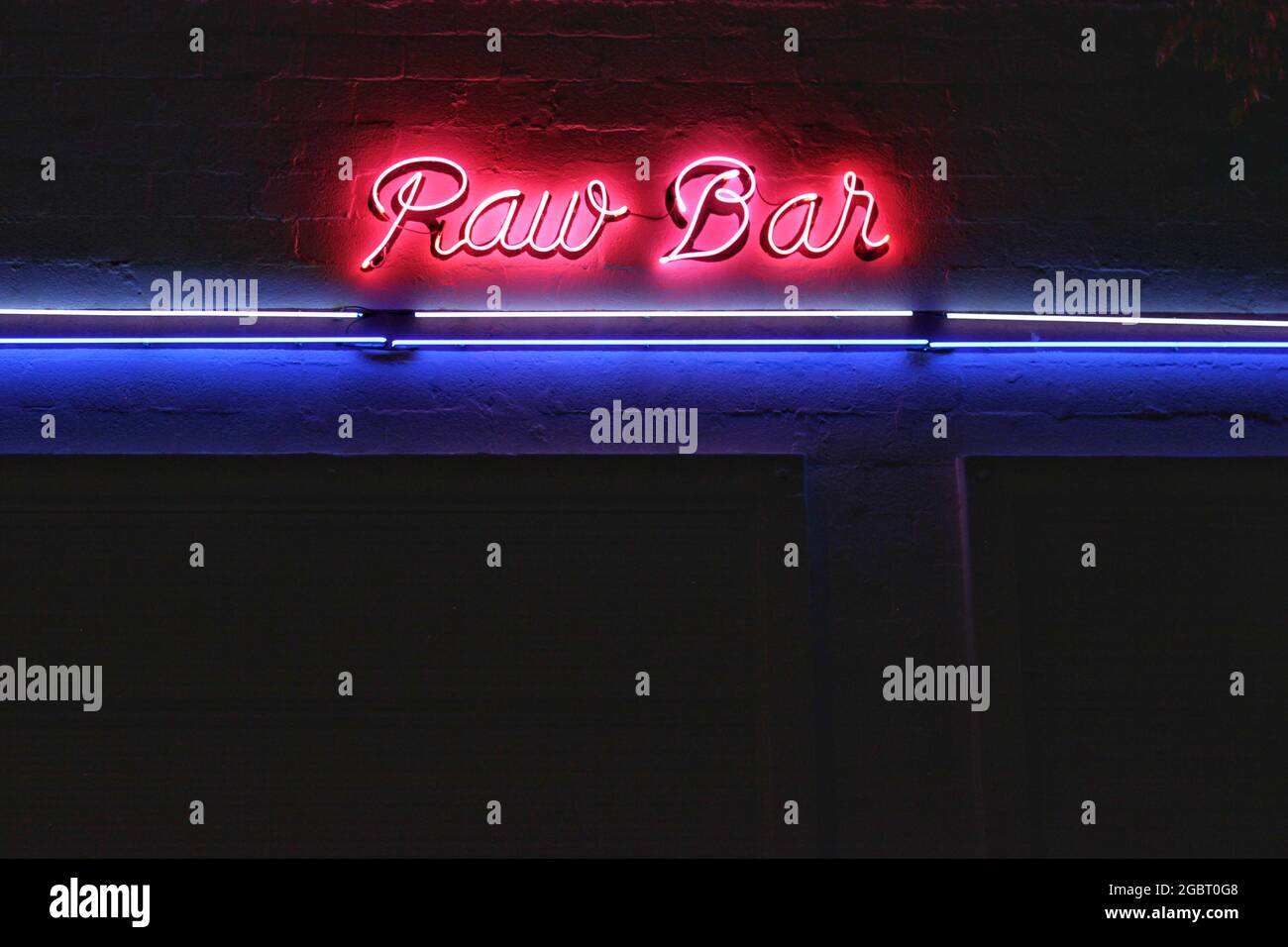 A brightly colored neon sign announcing a raw bar Stock Photo - Alamy