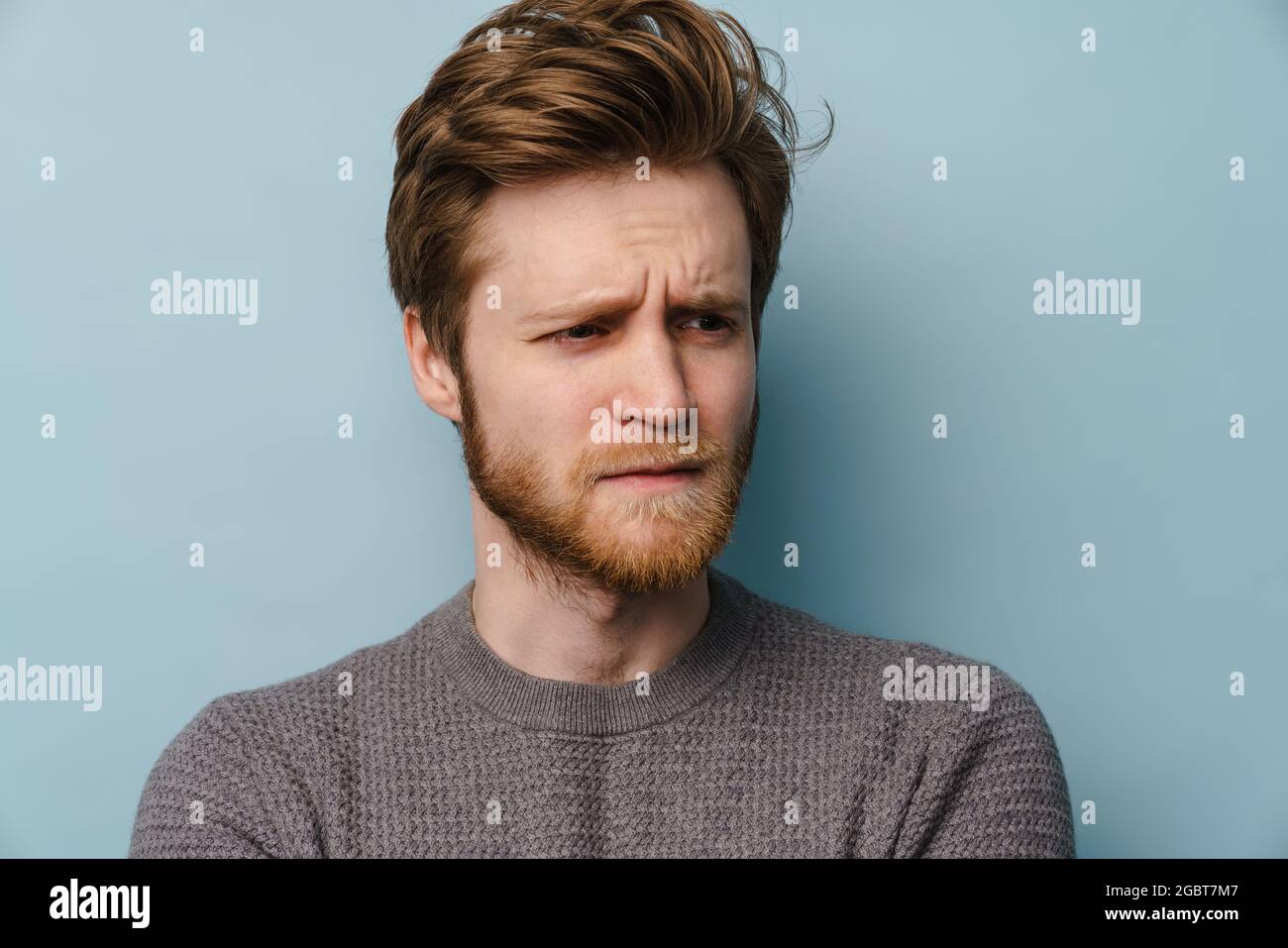 White ginger man with beard frowning and looking aside isolated over ...