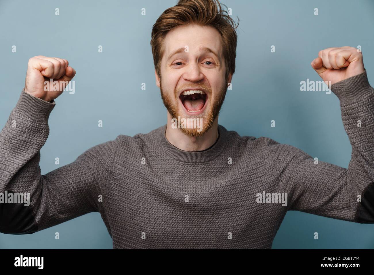 Bearded ginger man screaming and making winner gesture isolated over ...