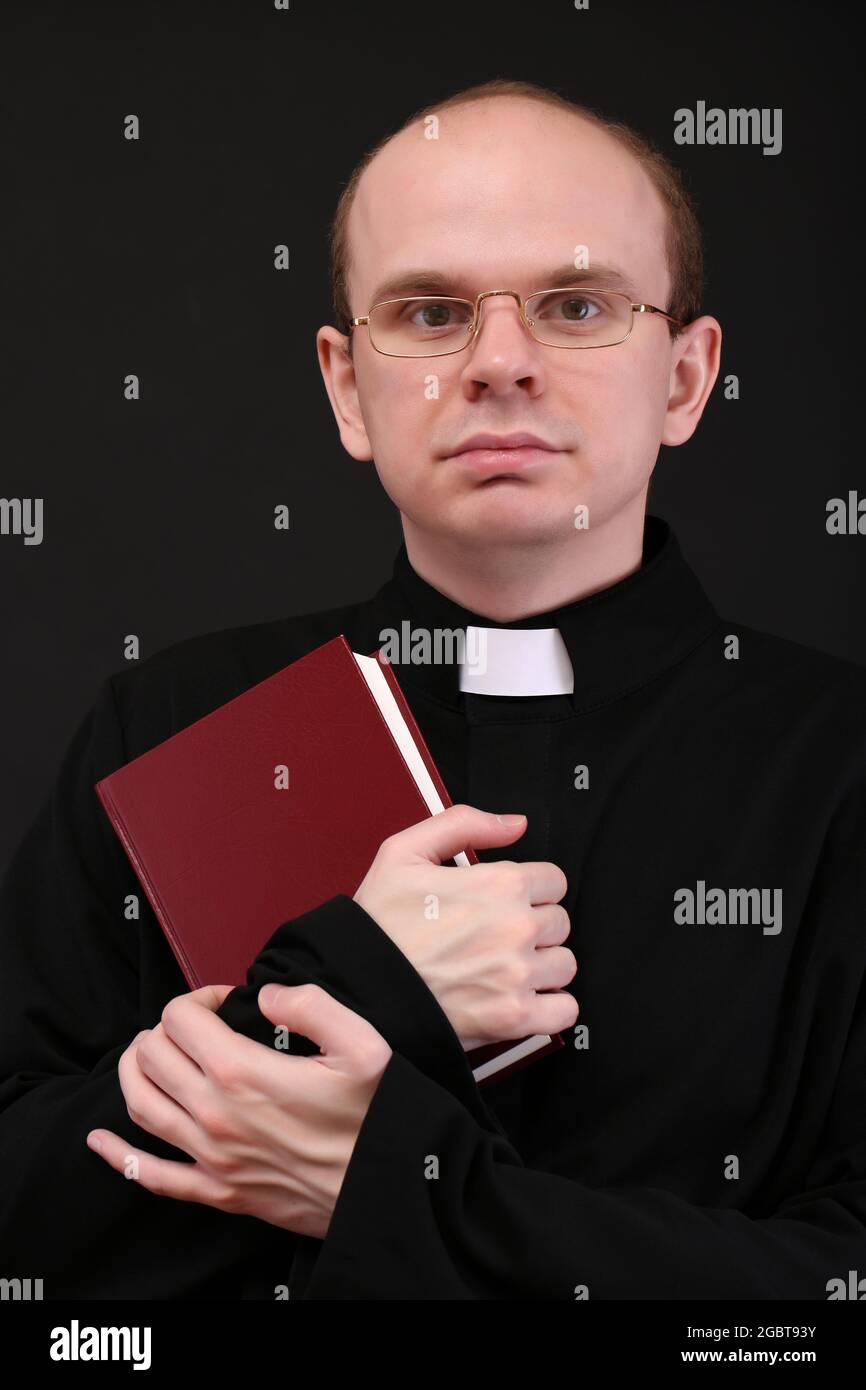 Young pastor with Bible, isolated on black Stock Photo - Alamy