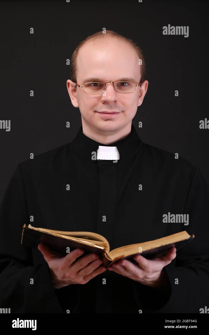 Young pastor with Bible, isolated on black Stock Photo - Alamy