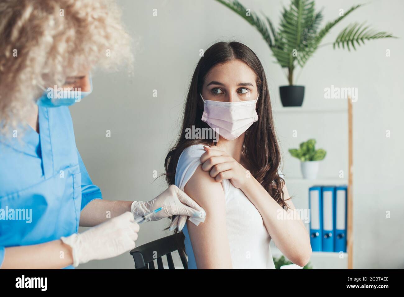 Young woman getting vaccinated by a nurse in a medical room Stock Photo ...