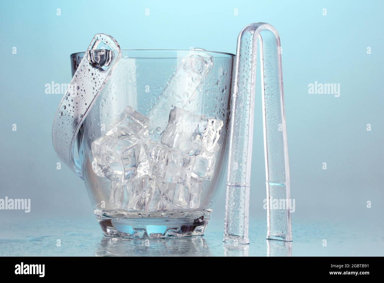 Glass ice bucket on light blue background Stock Photo - Alamy