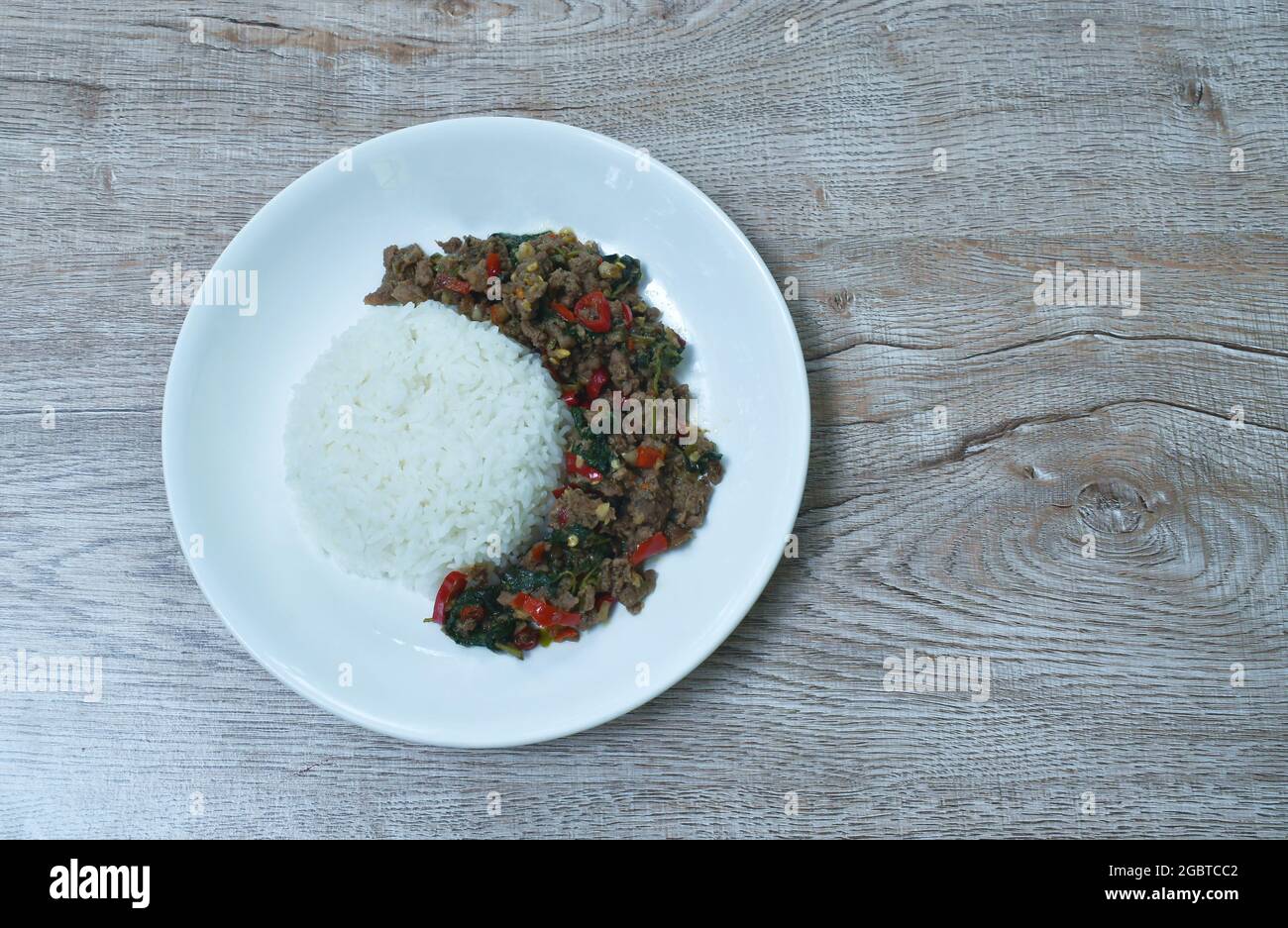spicy stir fried chop beef with basil leaf and chili on rice in plate ...