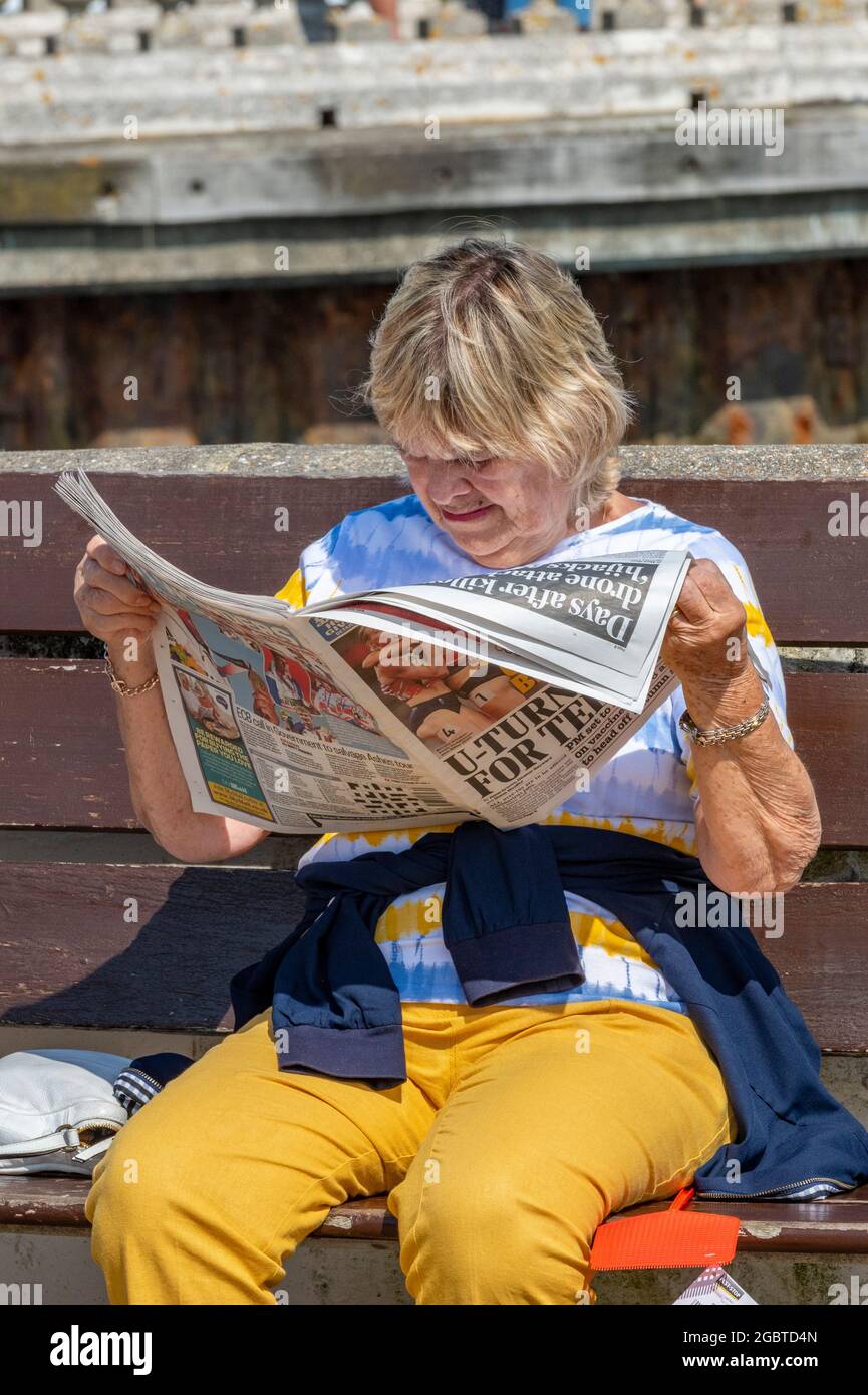 older lady reading a newspaper, middle-aged lady seated reading ...