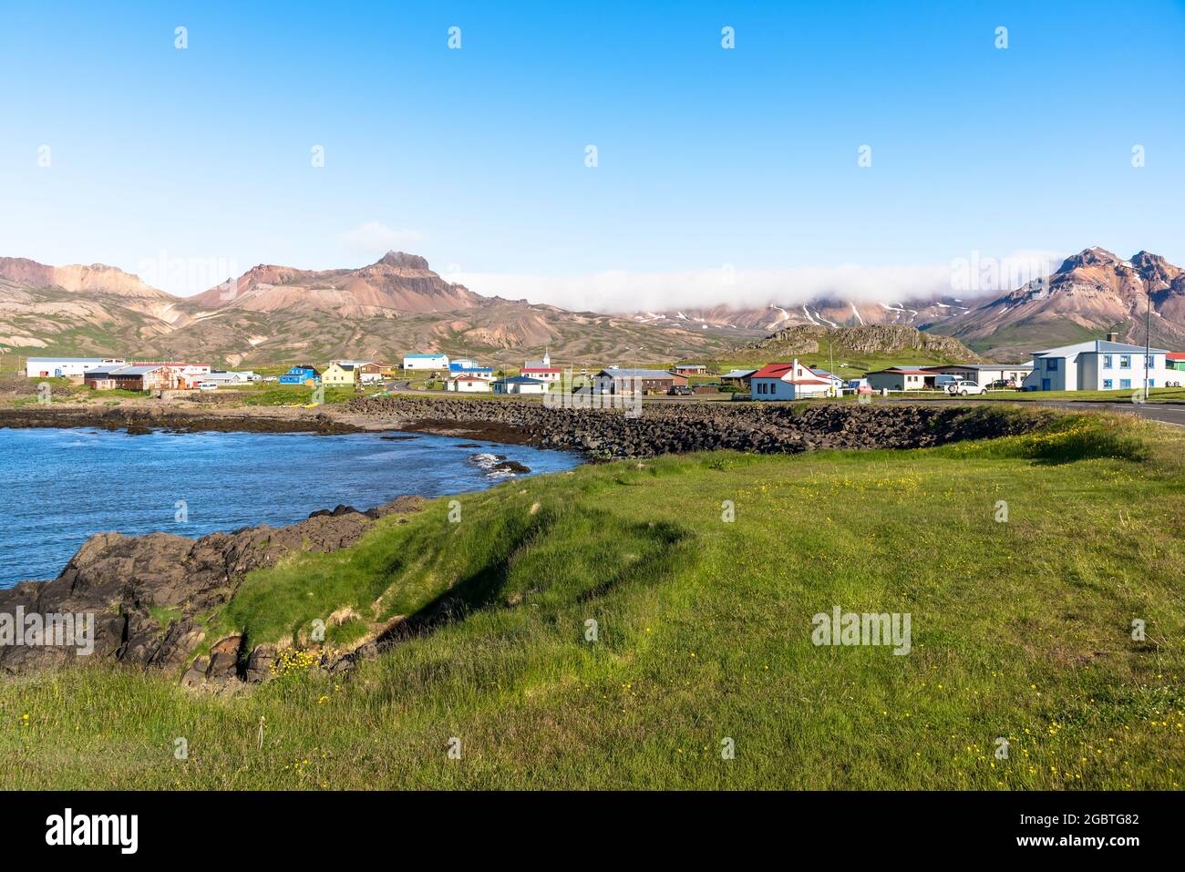 Small fjord village at the foot of towering mountains in Iceland on a ...